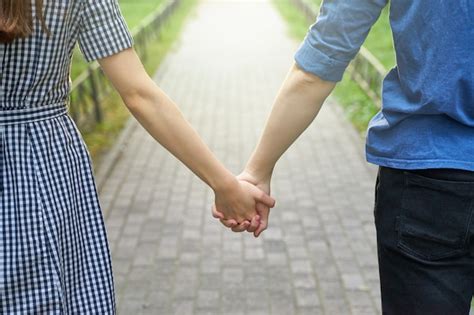Premium Photo Couple Holding Hands While Walking In The Park Closeup