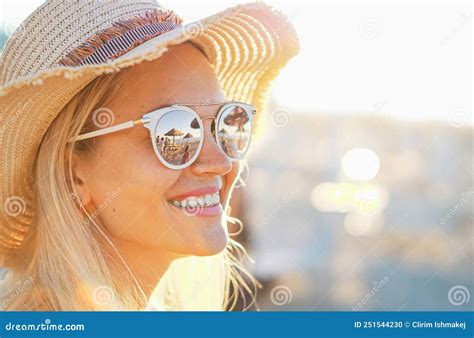 A Blonde Girl Smiling With Hat On Beach And Sunlight Reflected In