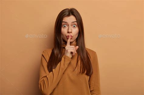Brunette European Woman Keeps Index Finger On Lips Make Hush Gesture