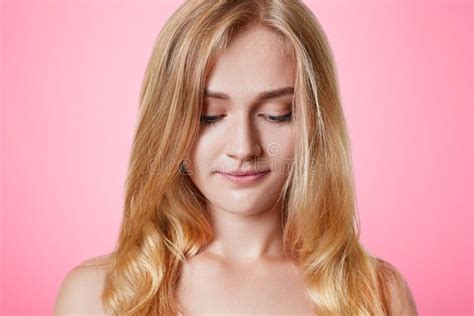 Serious Blonde Female With Appealing Apearance Looks Down Has Shy