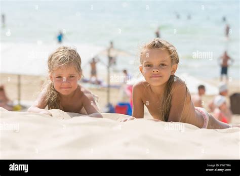 Two Girls Lying On The Sand On The Beach And Look At The Frame Stock