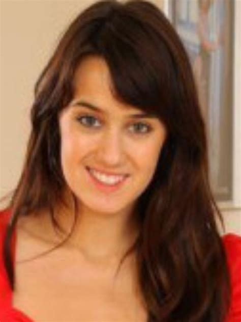 A Woman In A Red Top Smiling At The Camera With Long Dark Hair And Blue