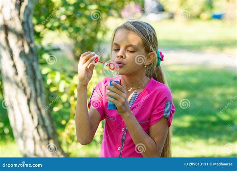 Flickan Blåser Upp Tvålbubblor På En Ljusstark Solnydag I Parken
