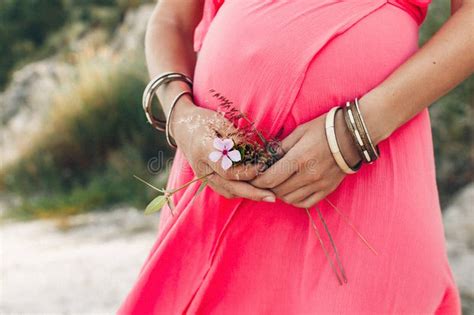 Close Up Of Tummy Of Pregnant Woman Wearing Long Red Dress Outdo Stock