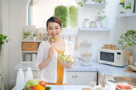 Premium Photo Young Smiling Woman Eating Vegetables Salad At Kitchen