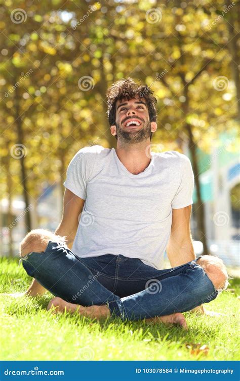 Portrait Of Handsome Man Sitting Outside In Grass Leaning Back Laughing
