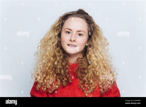 Satisfied Adorable Blue Eyed Female With Curly Light Hair Wears Red