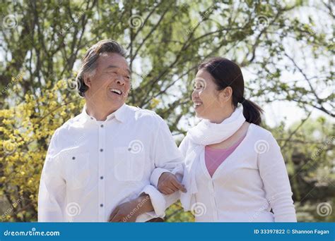 Happy Senior Couple Holding Hands And Going For A Walk In The Park In