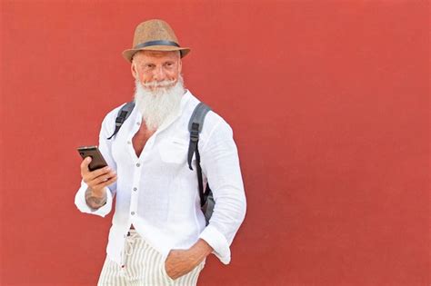 Premium Photo Smiling Man Holding Mobile Phone While Standing Against