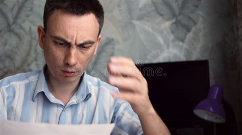 Frustrated Man Sitting At Desk With Paper Bills Bankruptcy Concept