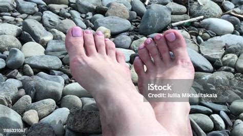 Woman Bare Feet Sitting Relaxing On The Beach Covered With Pebble Close