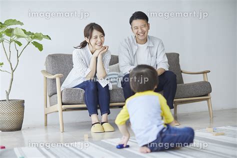 おもちゃで遊ぶ子供を見守る両親の写真素材 [129321921] イメージマート