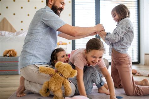 Father With Three Daughters Indoors At Home Playing On Floor Stock