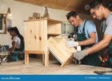 Professional Carpenters Assembling Wooden Cabinet In Workshop Stock