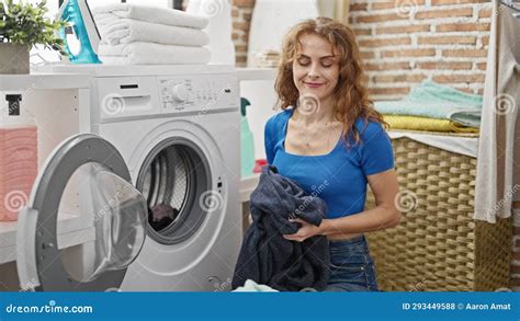 Young Woman Smelling Clean Clothes Doing Thumb Up Gesture At Laundry