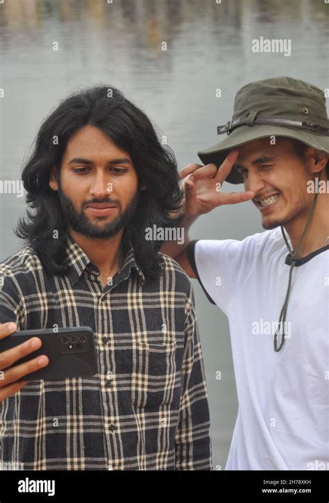 Two Male Friends Having Fun While Taking Selfie Together In Beside Of