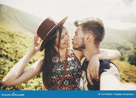 Stylish Hipster Couple Taking Selfie And Kissing On Top Of Mount Stock