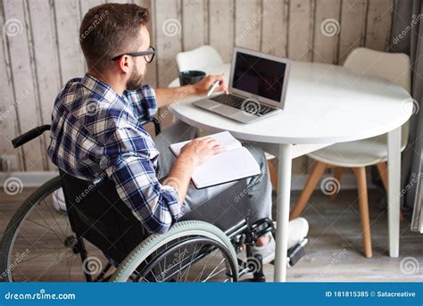 Disabled Young Man Making Notes In Notepad While Using Laptop Stock
