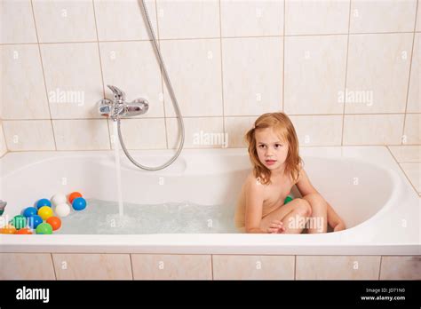 Ein Kleines Mädchen In Eine Badewanne Mit Farbigen Kugeln Spielen
