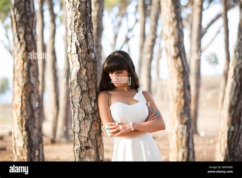 Beautiful Woman Arms Folded Leaning Against A Tree Looking Down Stock