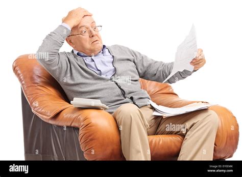 Shocked Senior Gentleman Looking At His Bills In Disbelief Seated In An