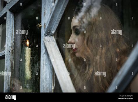 Beautiful Sad Young Girl Looking Out The Window With A Candle Good For