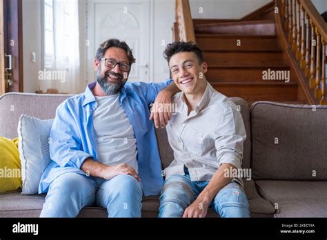 Happy Father And Son Sitting On Sofa At Home Cheerful Father With