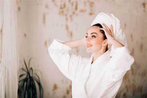 Attractive Girl Wearing White Bathrobe And Towel On Head In Bathroom