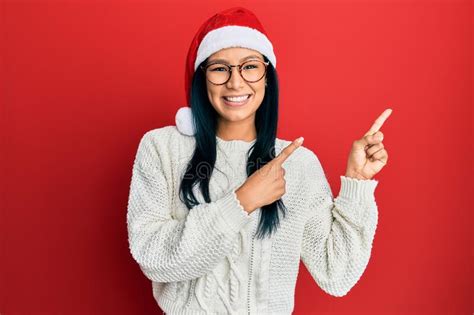 Beautiful Hispanic Woman Wearing Christmas Hat Smiling And Looking At