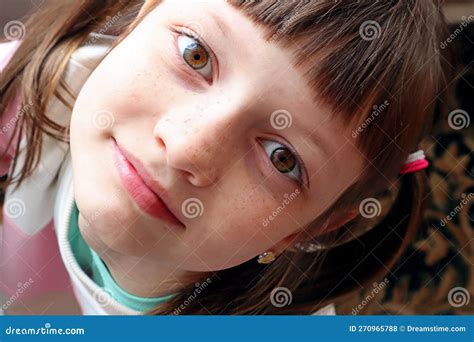 A Ten Year Old Girl With Brown Eyes Looks Up From The Bottom Close Up
