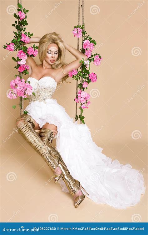 Beautiful Blonde Bride In A Wedding Dress On A Swing Decorated With