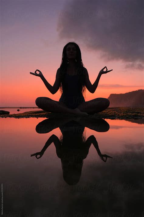 Silhouette Young Woman Practicing Yoga On The Beach At Sunset By