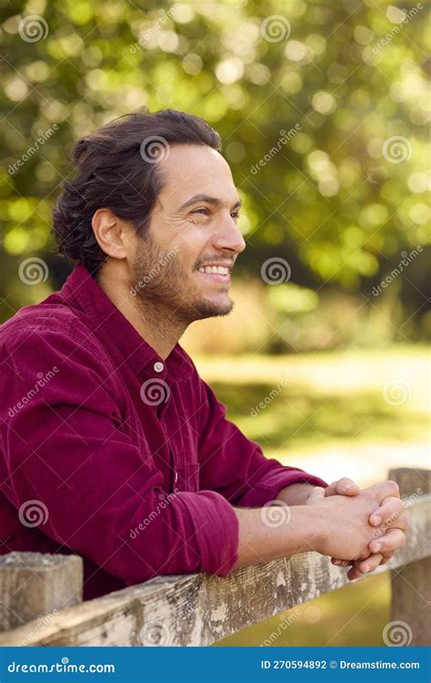 Portrait Of Smiling Casually Dressed Mature Man Leaning On Fence On