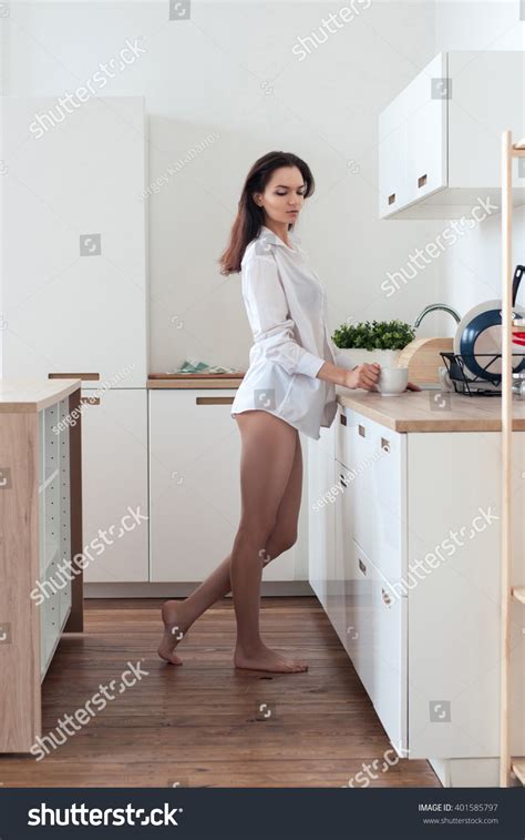 Beautiful Barefoot Female Standing In Kitchen On Wood Floor And Holding