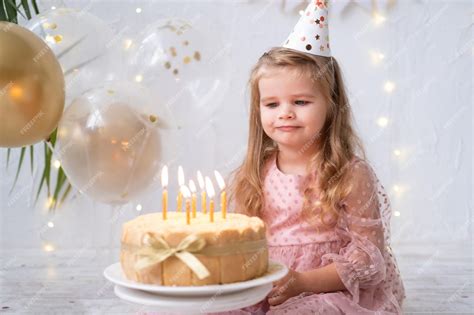 생일 케이크에 촛불을 불고 생일을 축하하는 귀여운 어린 소녀 프리미엄 사진