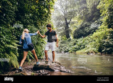 Couple Of Hikers In Forest Young Man Helping Woman While Walking By