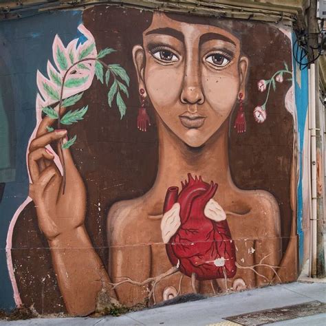 A Mural On The Side Of A Building Depicts A Woman Holding A Heart And