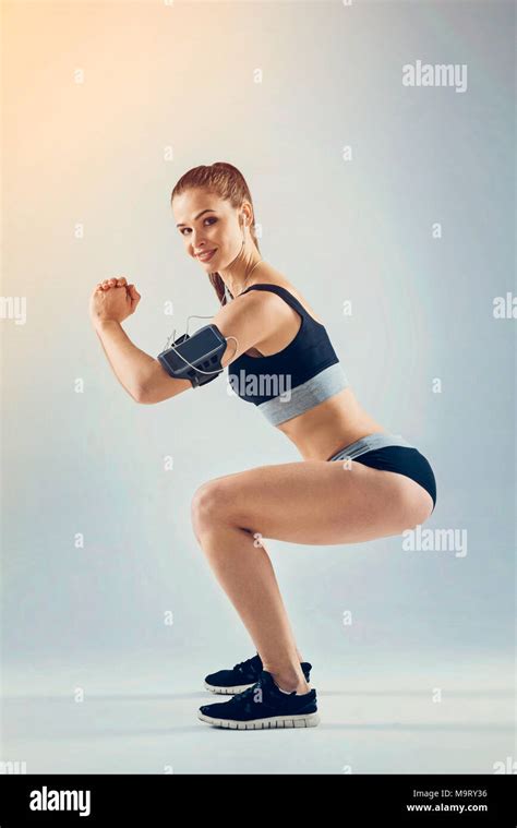 Joyful Young Female Athlete Doing Squat Exercise And Smiling Stock