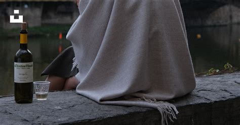 와인 한 병과 함께 난간에 앉아 있는 여자 사진 Unsplash의 무료 유행 이미지