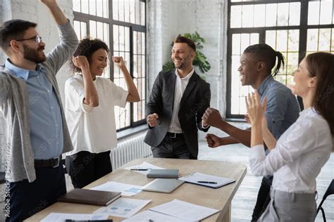 Excited Diverse Employees Celebrating Great Teamwork Result At Meeting
