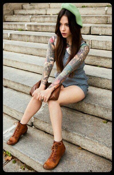 A Woman Sitting On The Steps With Her Legs Crossed And Tattoos On Her Arm