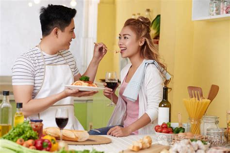 年轻的亚裔男子喂养他漂亮的女朋友与意大利面条 他做了照片 正版商用图片0b36q9 摄图新视界