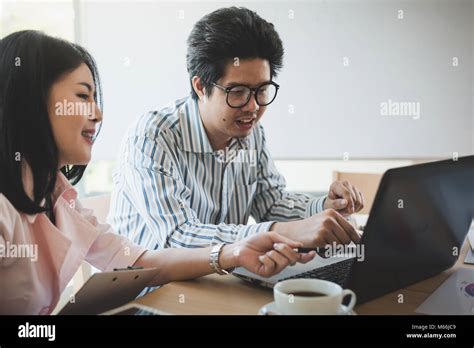 Young Asian Businessman And Businesswoman Talking About Their Work