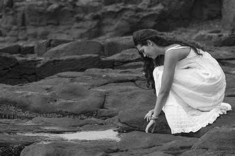 Premium Photo Side View Of Woman Crouching On Rock At Beach
