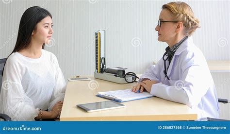 Asian Woman Patient Sitting With Doctor About Her Illness And Showing X