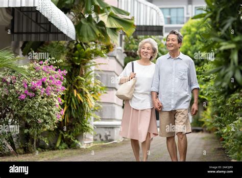 Happy Senior Chinese Couple Holding Hands And Walking Together Stock
