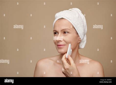 Smiling Middle Aged Woman Massaging Chin With Gua Sha After Shower