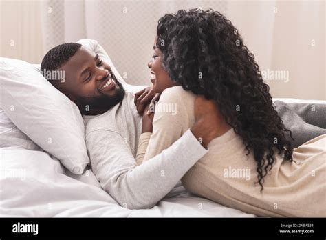 Smiling Black Couple Having Fun In Bed Embracing And Flirting Stock