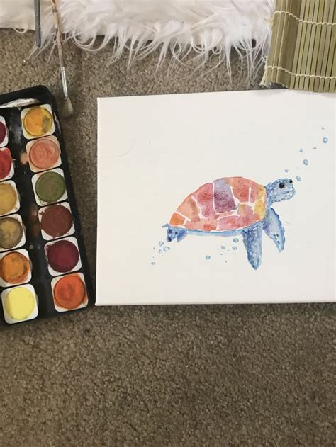 a painting with watercolors and paintbrushes on the floor next to it