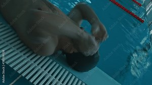 Medium shot with slow exposure effect of exhausted Caucasian male swimmer in black trunks, cap leaping out of pool, lying down, taking off goggles and catching breath, resting after high speed race